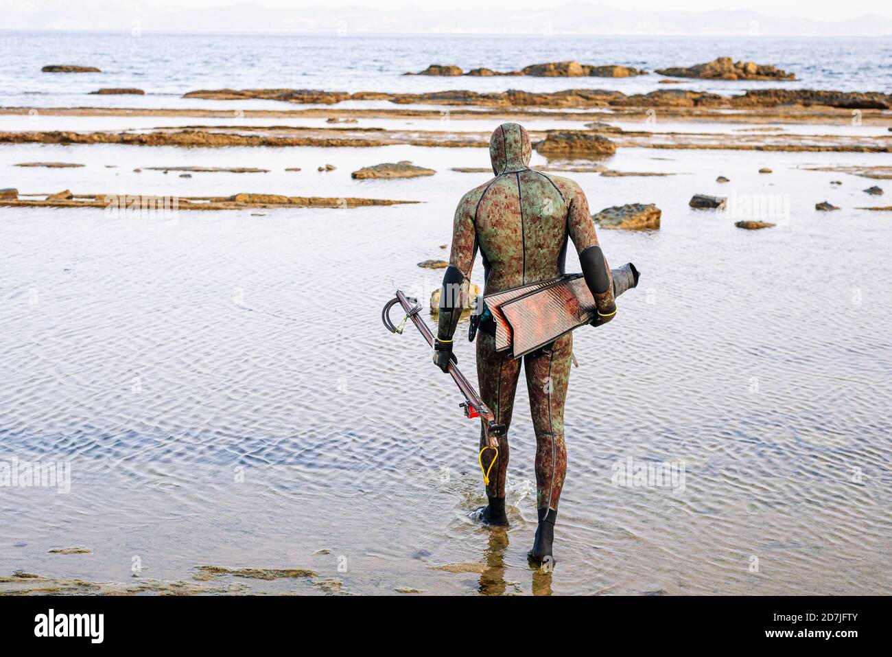 Mature man with harpoon and flipper walking at beach Stock Photo - Alamy