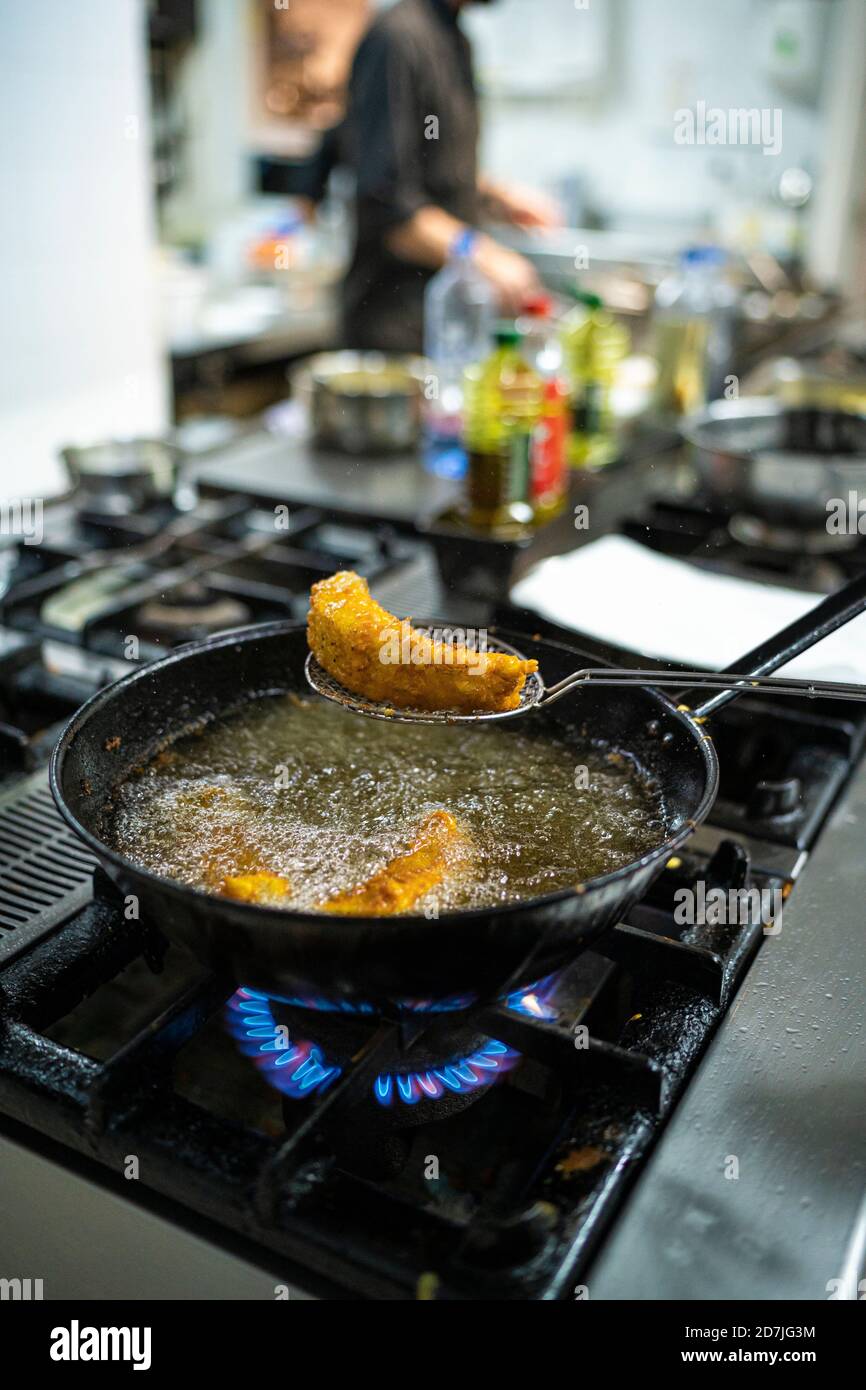 Cooking pan on gas stove burner with chef working in background at ...