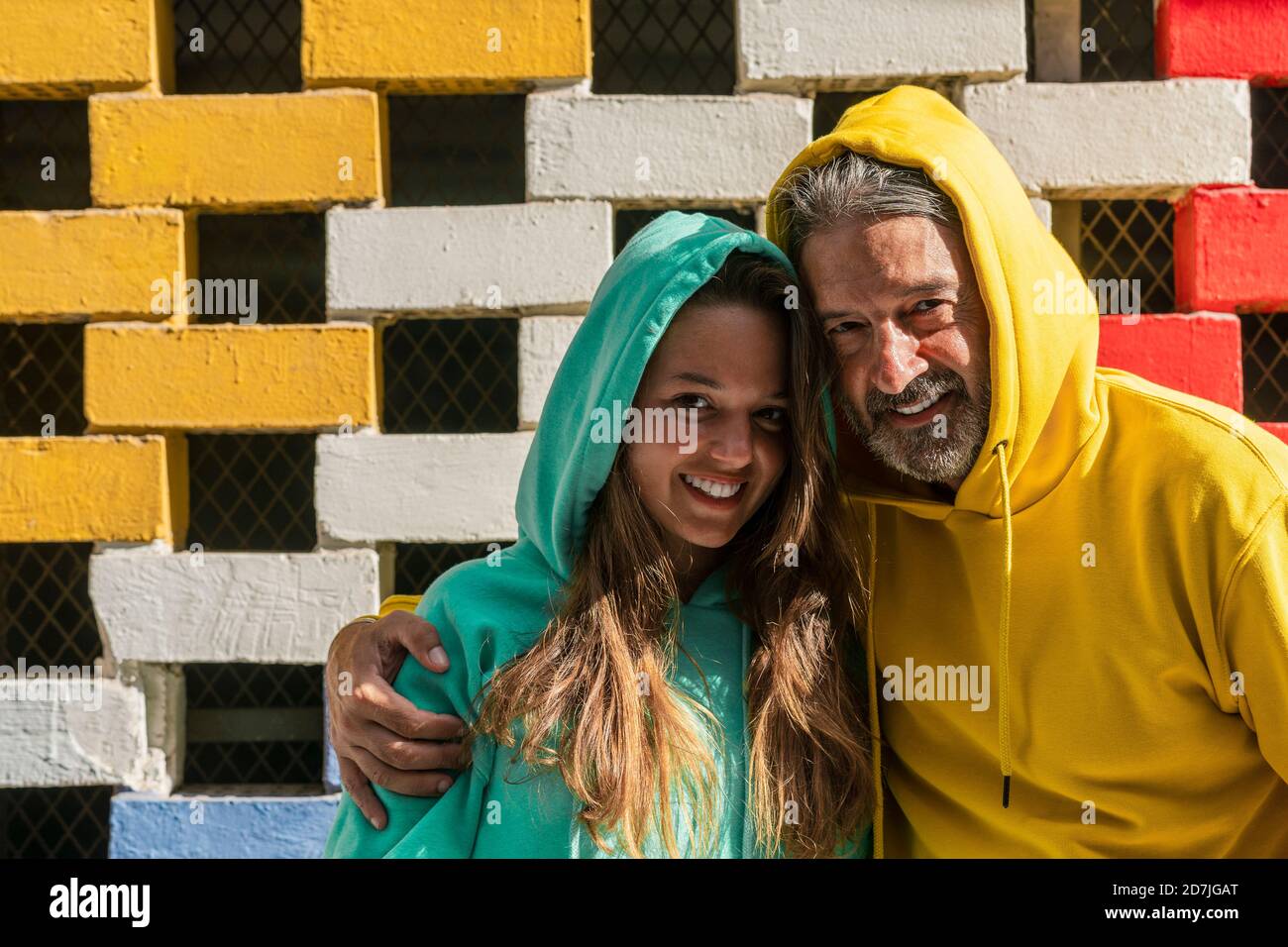 Smiling father and daughter standing against brick wall Stock Photo - Alamy