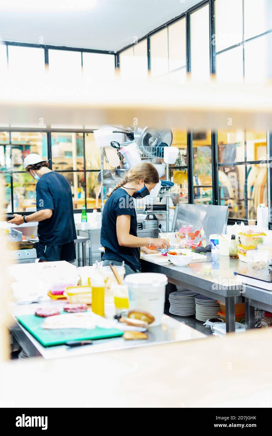 Chefs cooking in commercial kitchen at restaurant seen through window ...