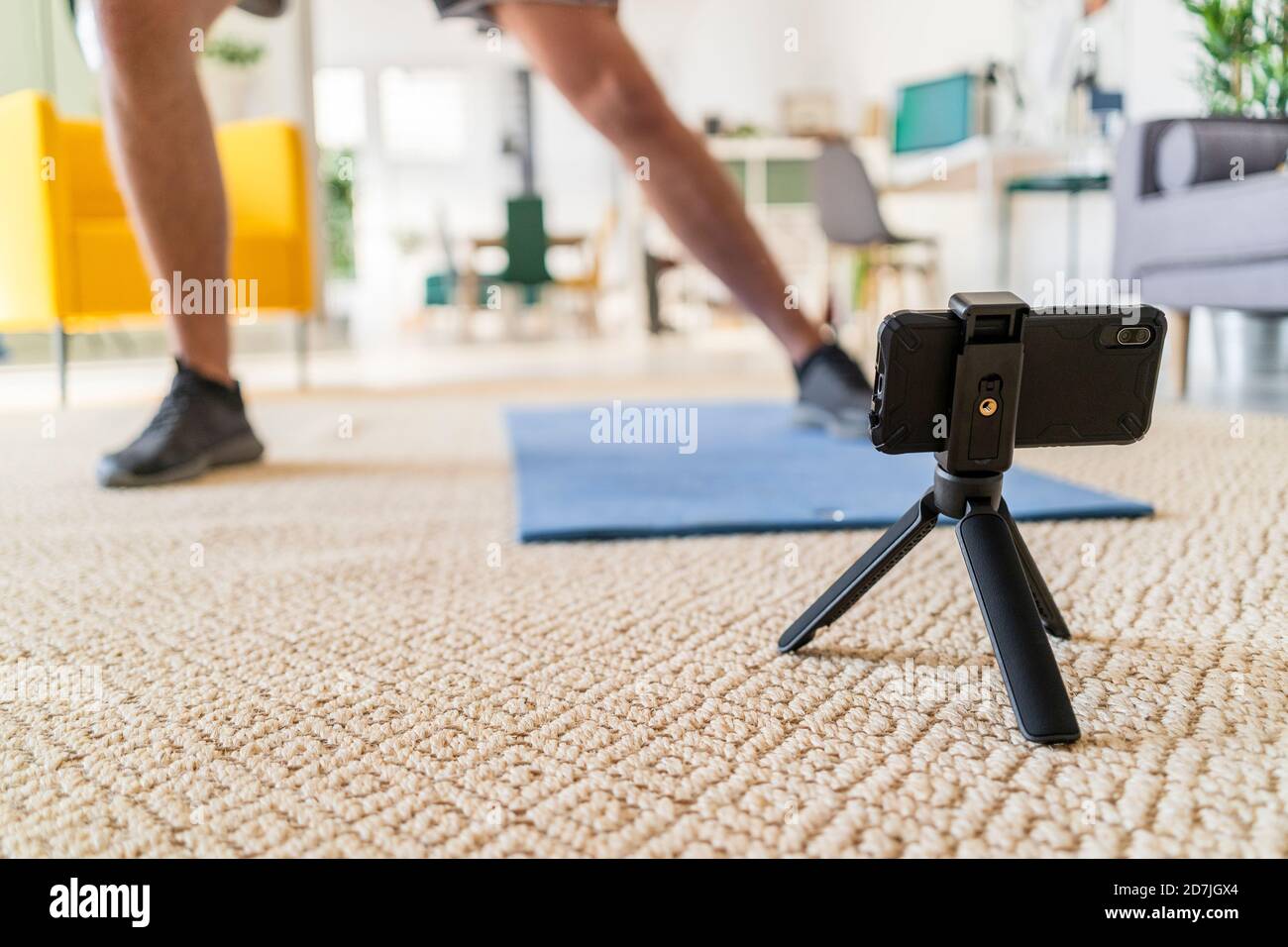 Tripod on floor with man exercising in background at home Stock Photo ...