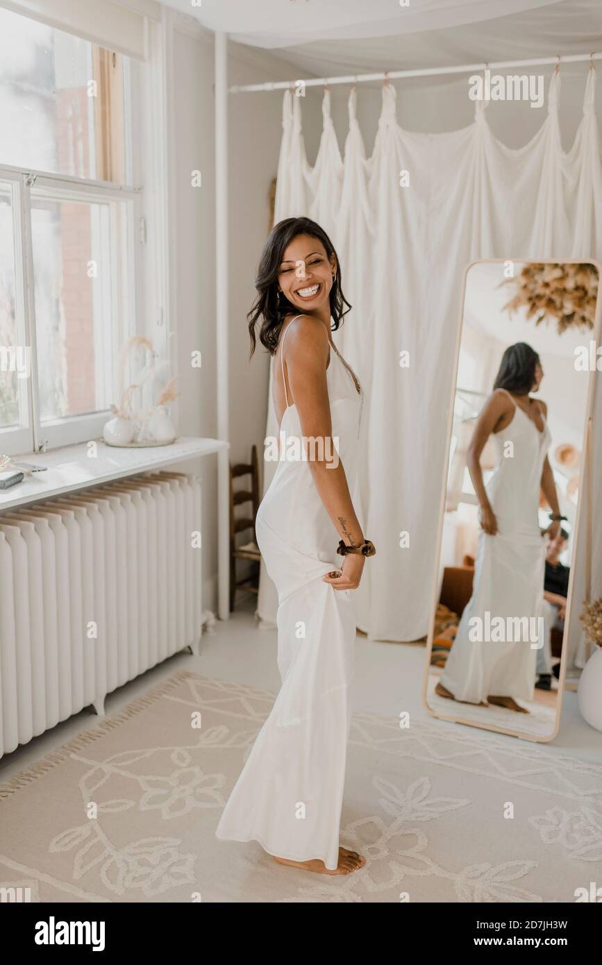 Reflection of smiling young bride standing at wedding dress shop Stock ...