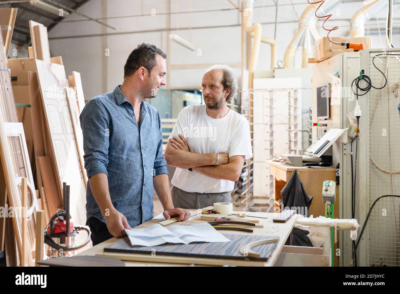 Smiling project manager talking with coworker while standing in factory ...