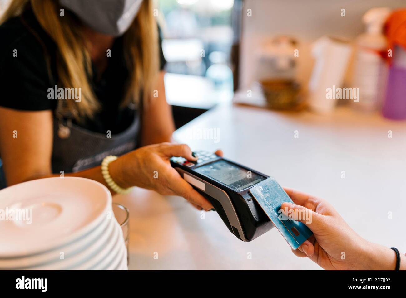 Female cashier receiving payment through credit card from customer in ...