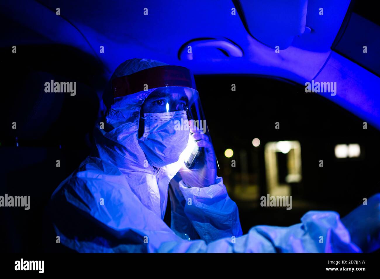 Male worker wearing workwear talking over mobile phone while driving ...