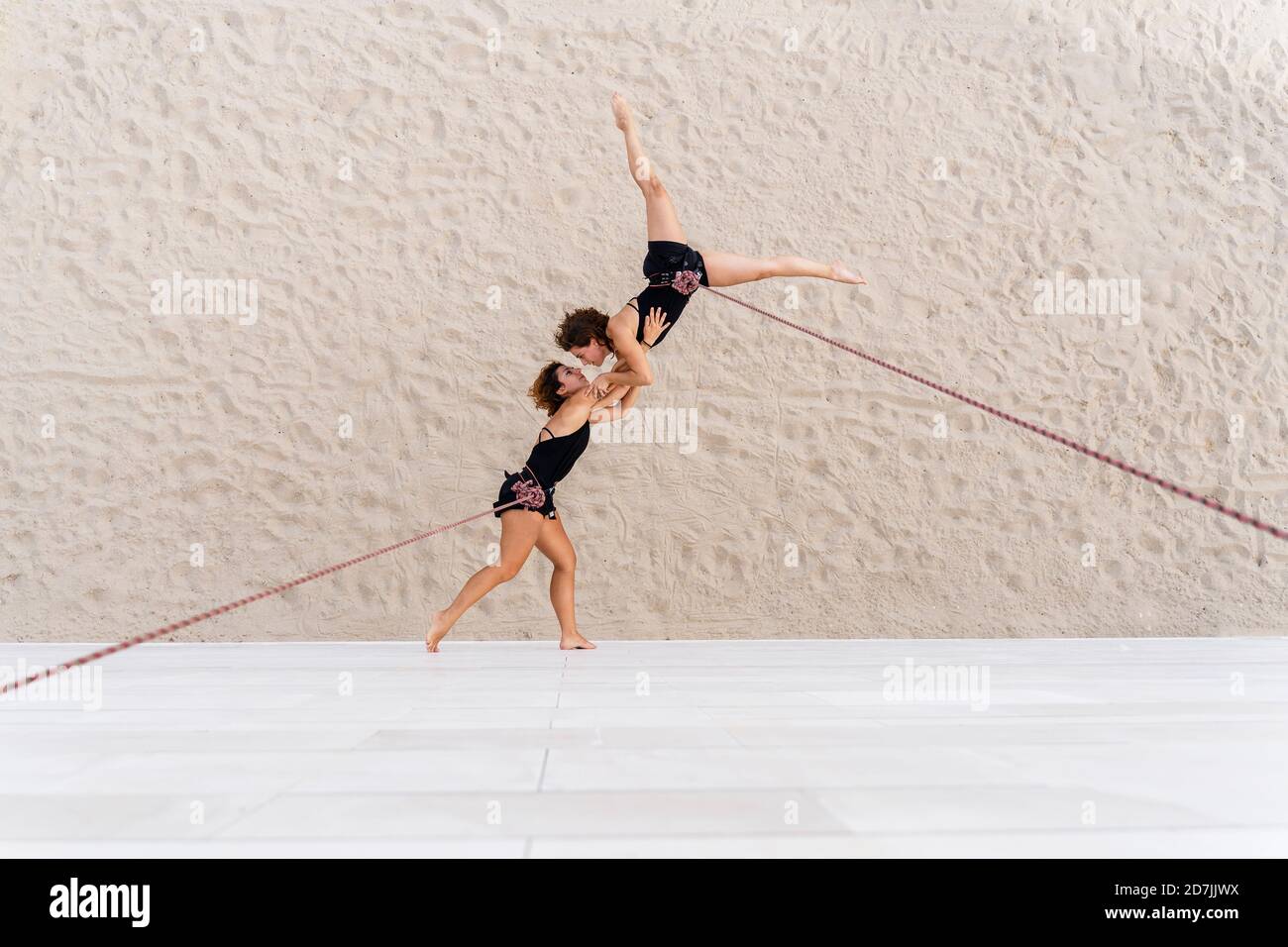 Aerial dancers dancing while hanging against wall Stock Photo - Alamy