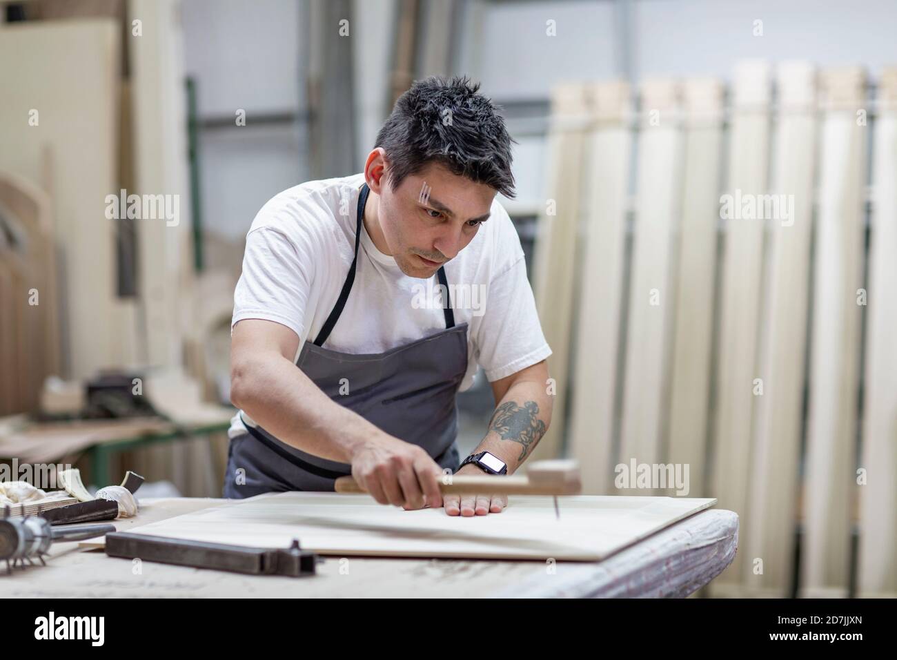 Artist giving design to wood through traditional method while standing ...