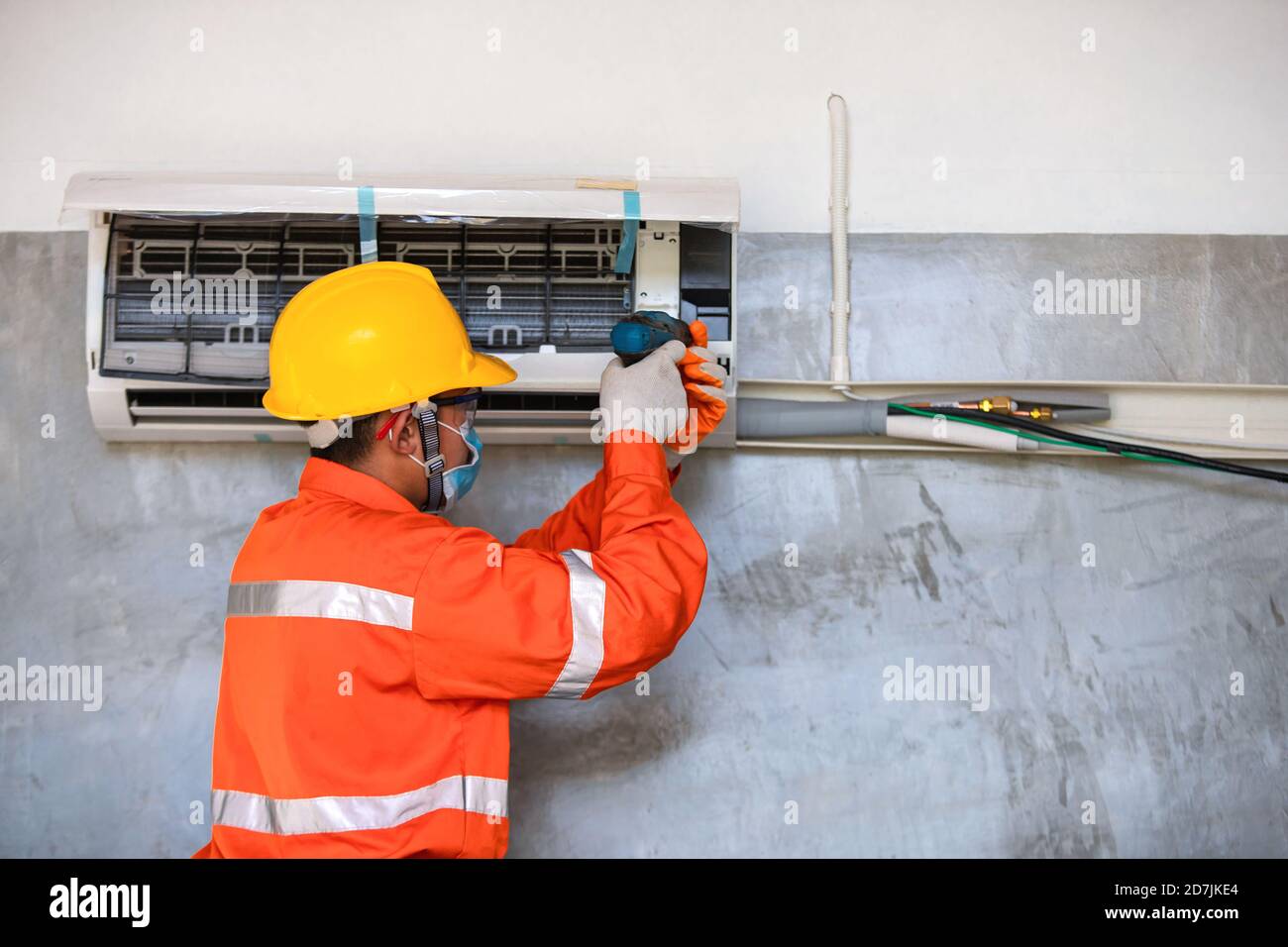 Air conditioner technician mechanic wearing mask and helmet to prevent ...