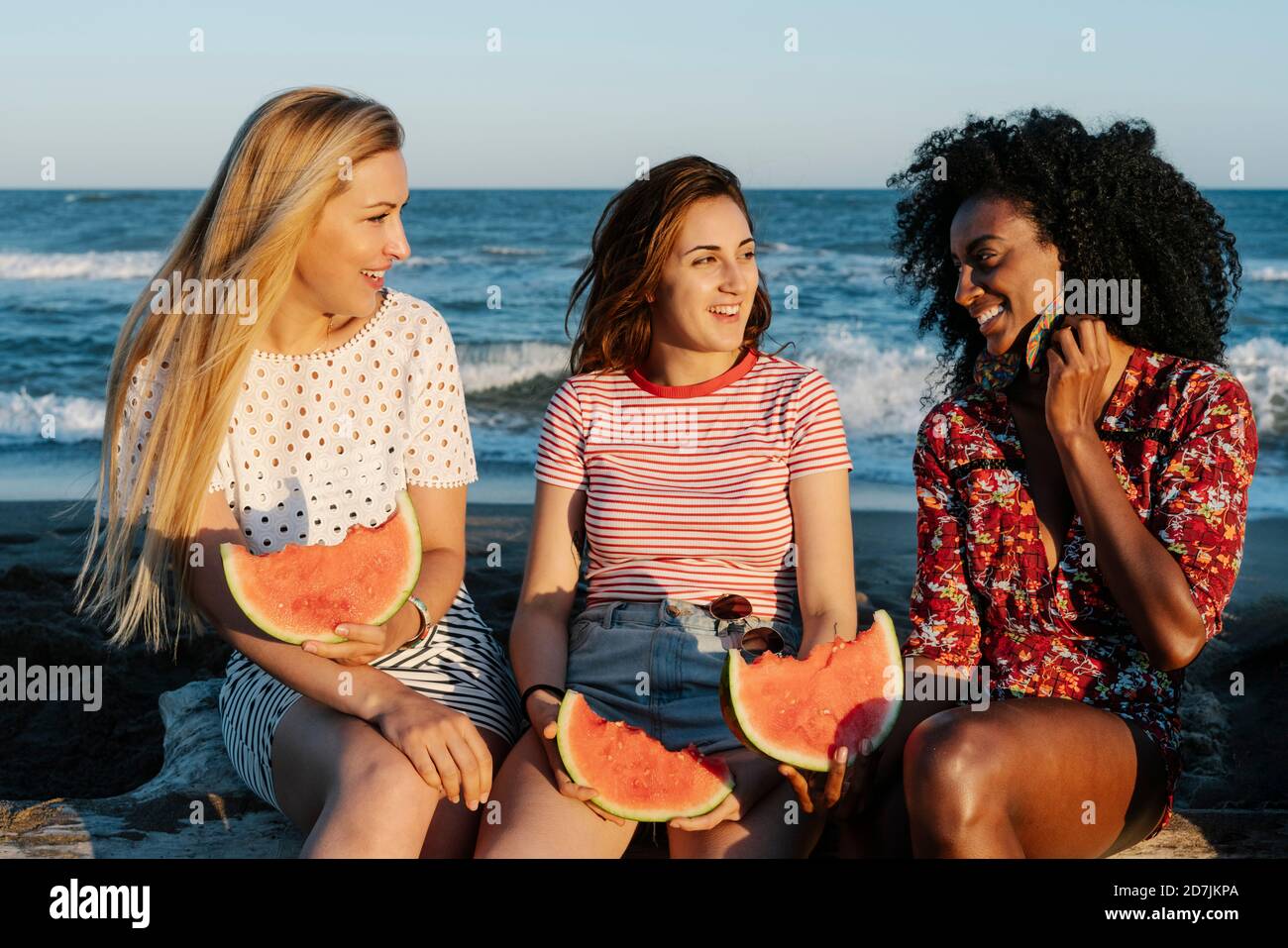 Friends spending time while eating watermelon on beach Stock Photo - Alamy