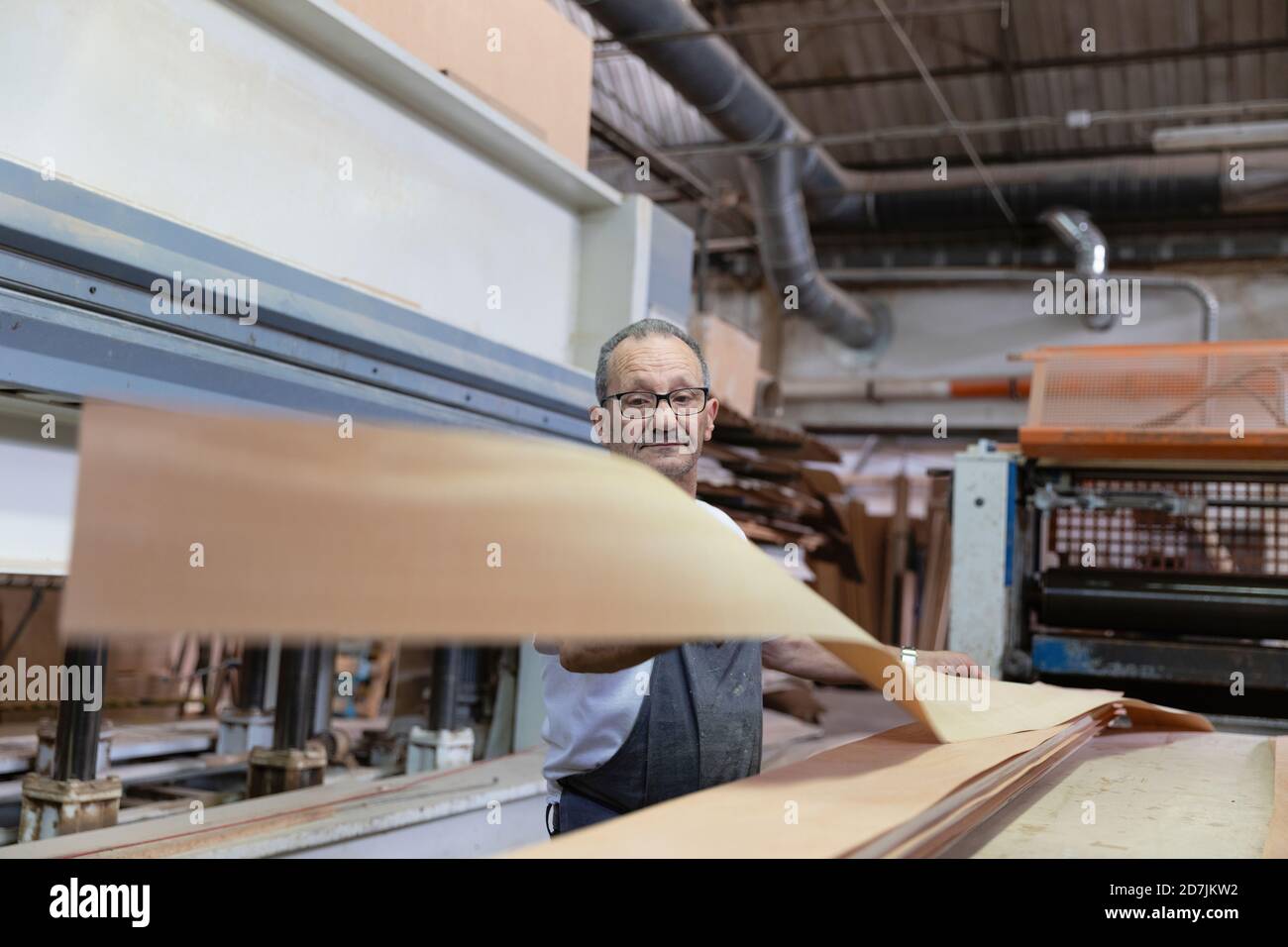 Man using wood laminating machine while standing in factory Stock Photo ...