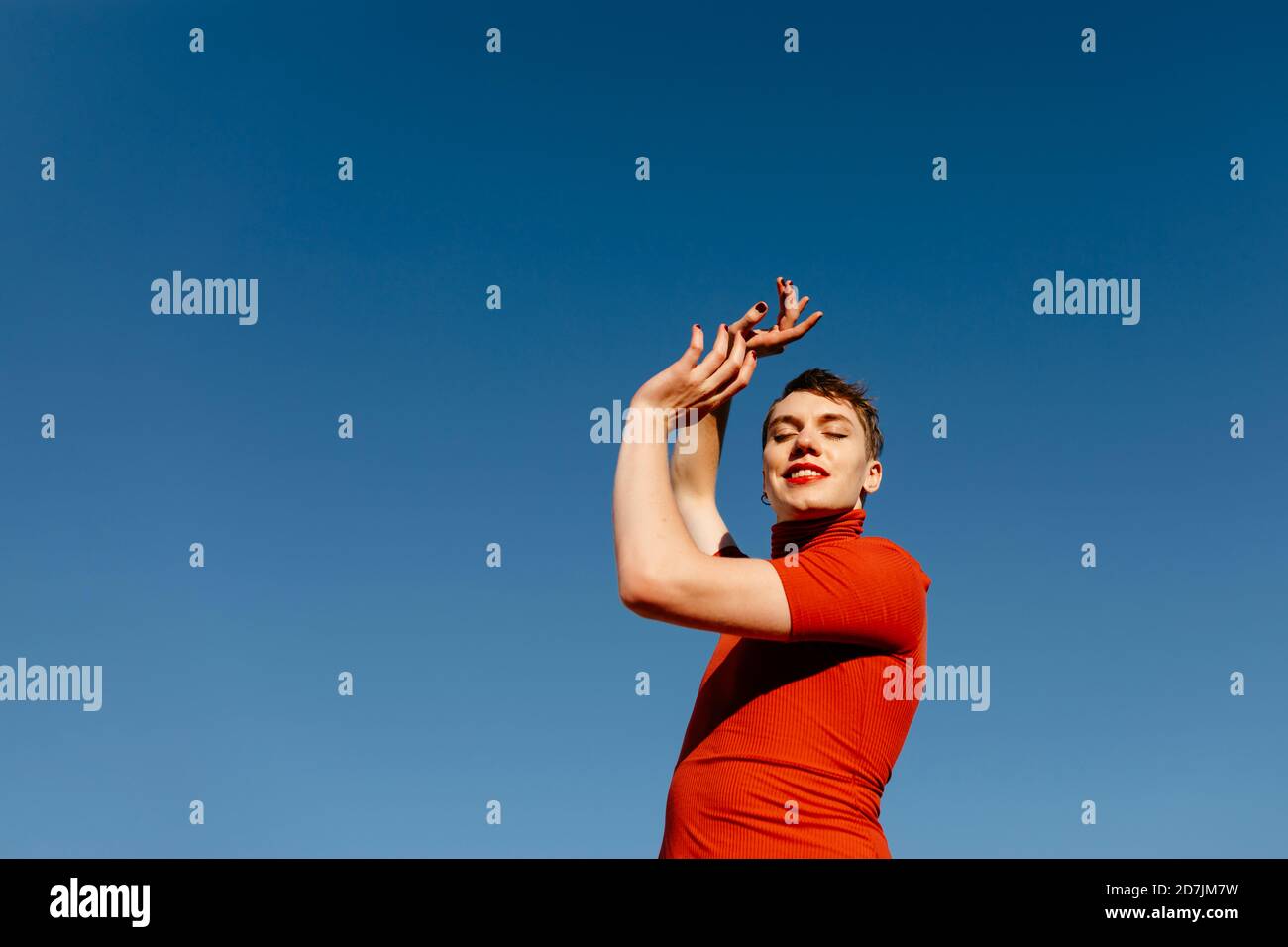 Non-binary man in red dress dancing against clear sky Stock Photo - Alamy