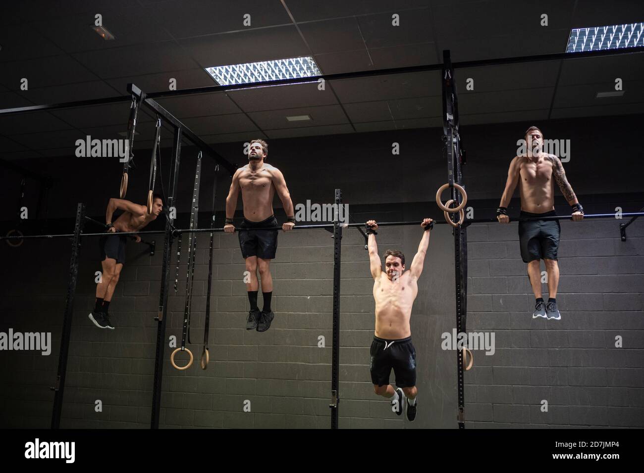 Athletes doing pull ups exercise on rod at gym Stock Photo - Alamy