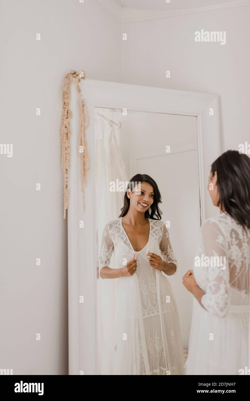 Reflection of young bride looking in mirror at wedding dress shop Stock ...
