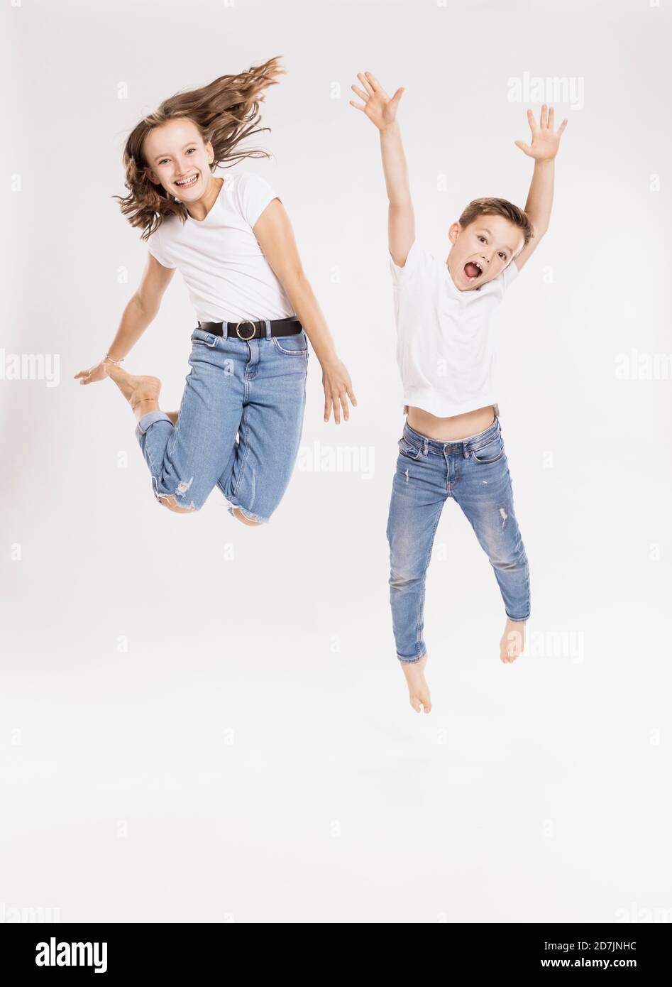 Cheerful siblings jumping against white background Stock Photo - Alamy