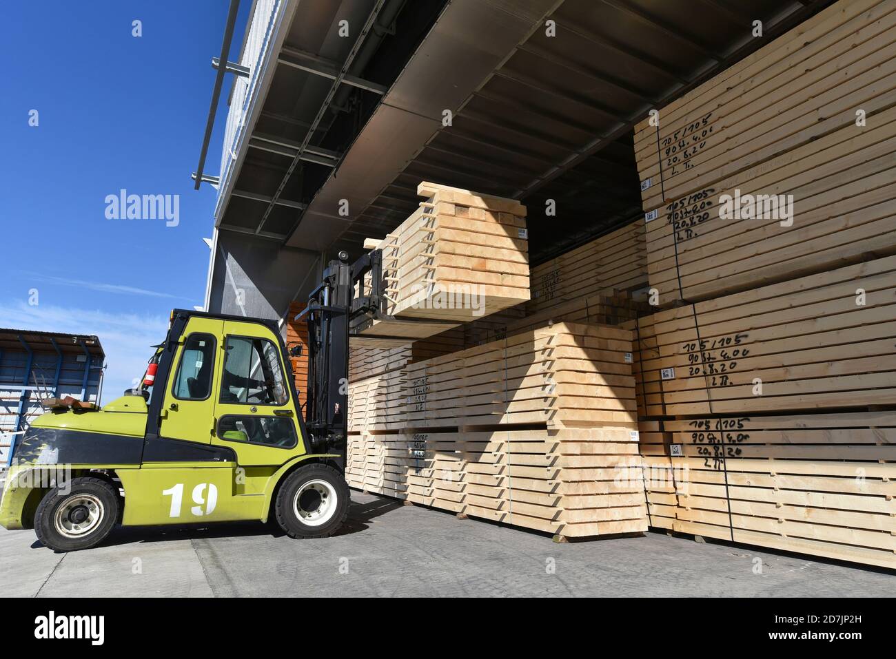 Forklift stacking planks inside lumberyard warehouse Stock Photo - Alamy