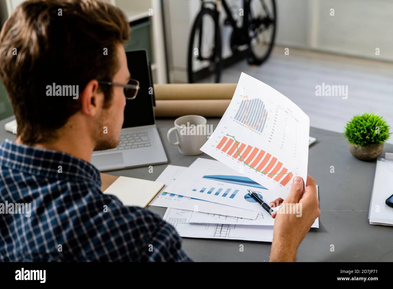 Architect analyzing graph while sitting by desk at office Stock Photo ...
