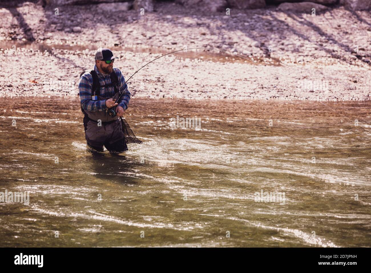 Fly fisherman catching fish from river on sunny day Stock Photo - Alamy