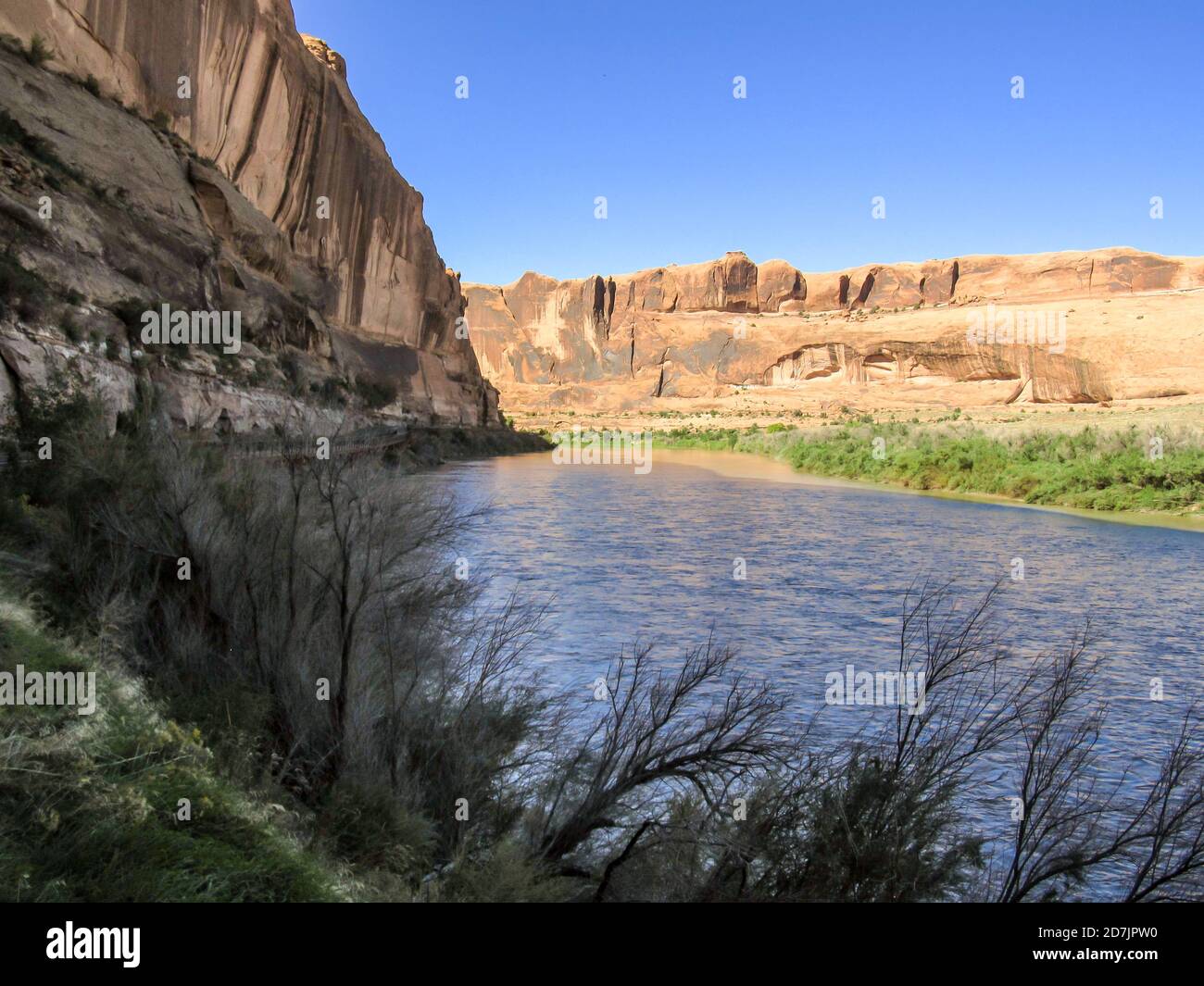 The Colorado River flowing between high reddish colored sandstone ...