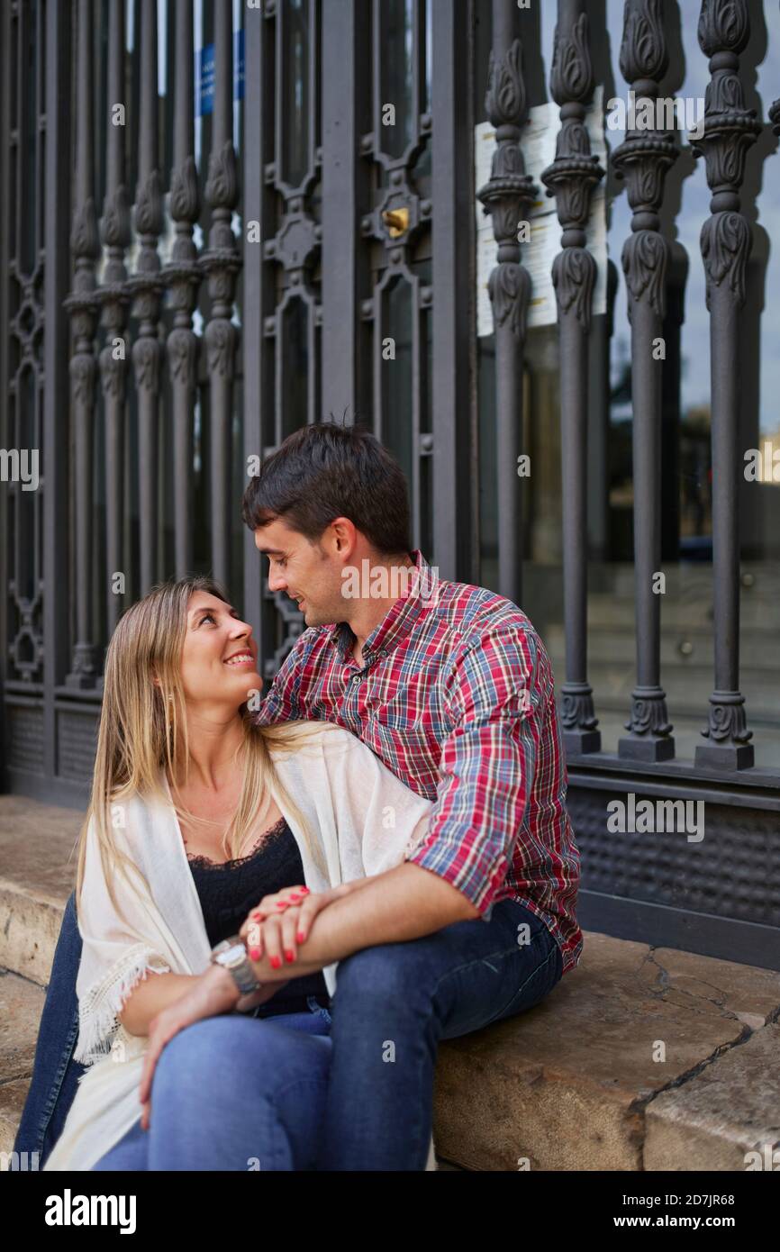 Couple sitting on steps against fence Stock Photo - Alamy
