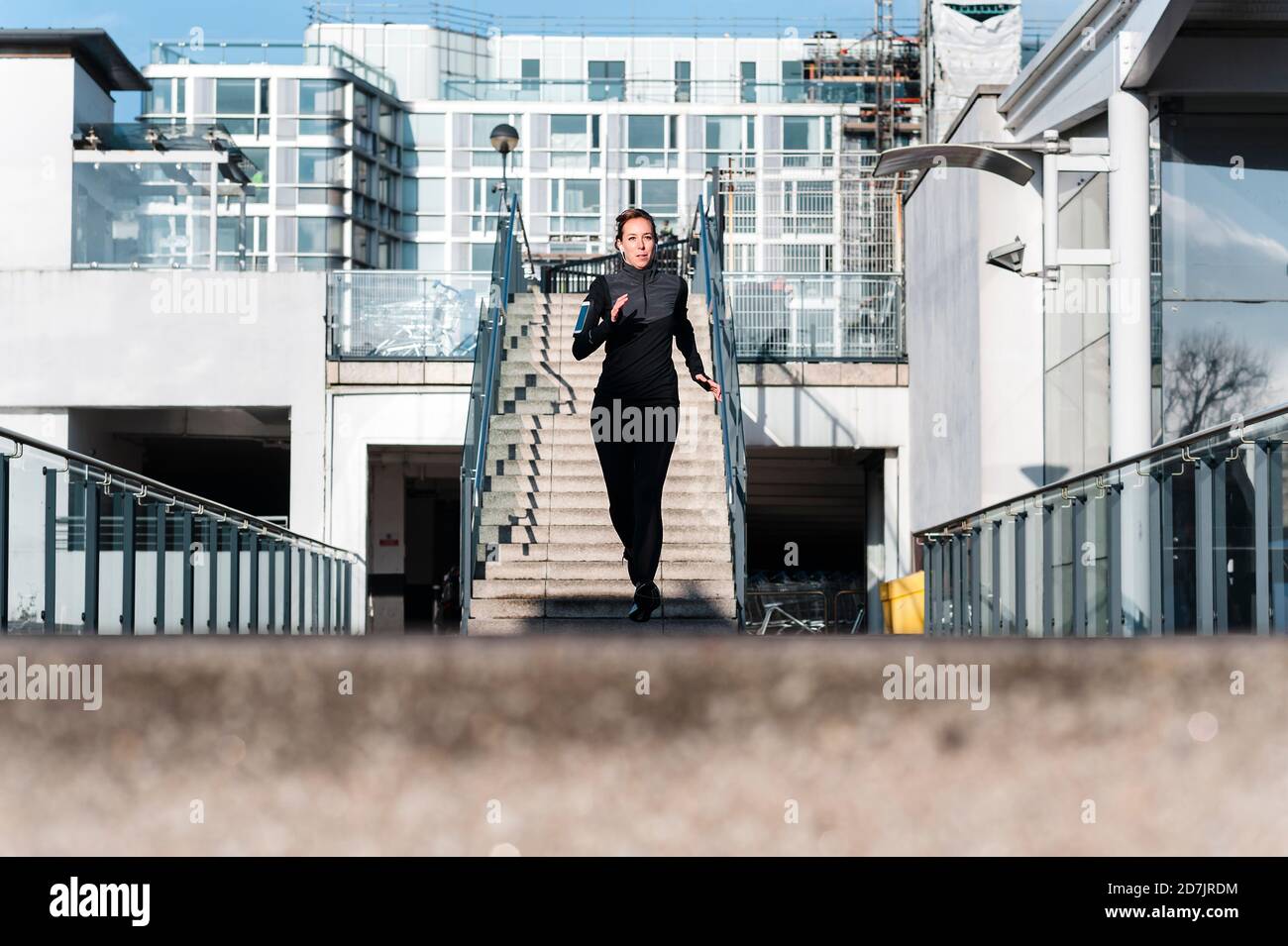 Female athlete running on rooftop in city during sunny day Stock Photo ...