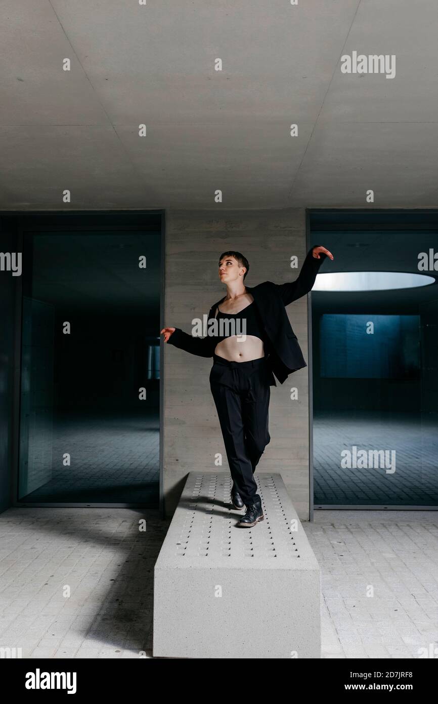 Non-binary young man dancing on seat in basement Stock Photo - Alamy