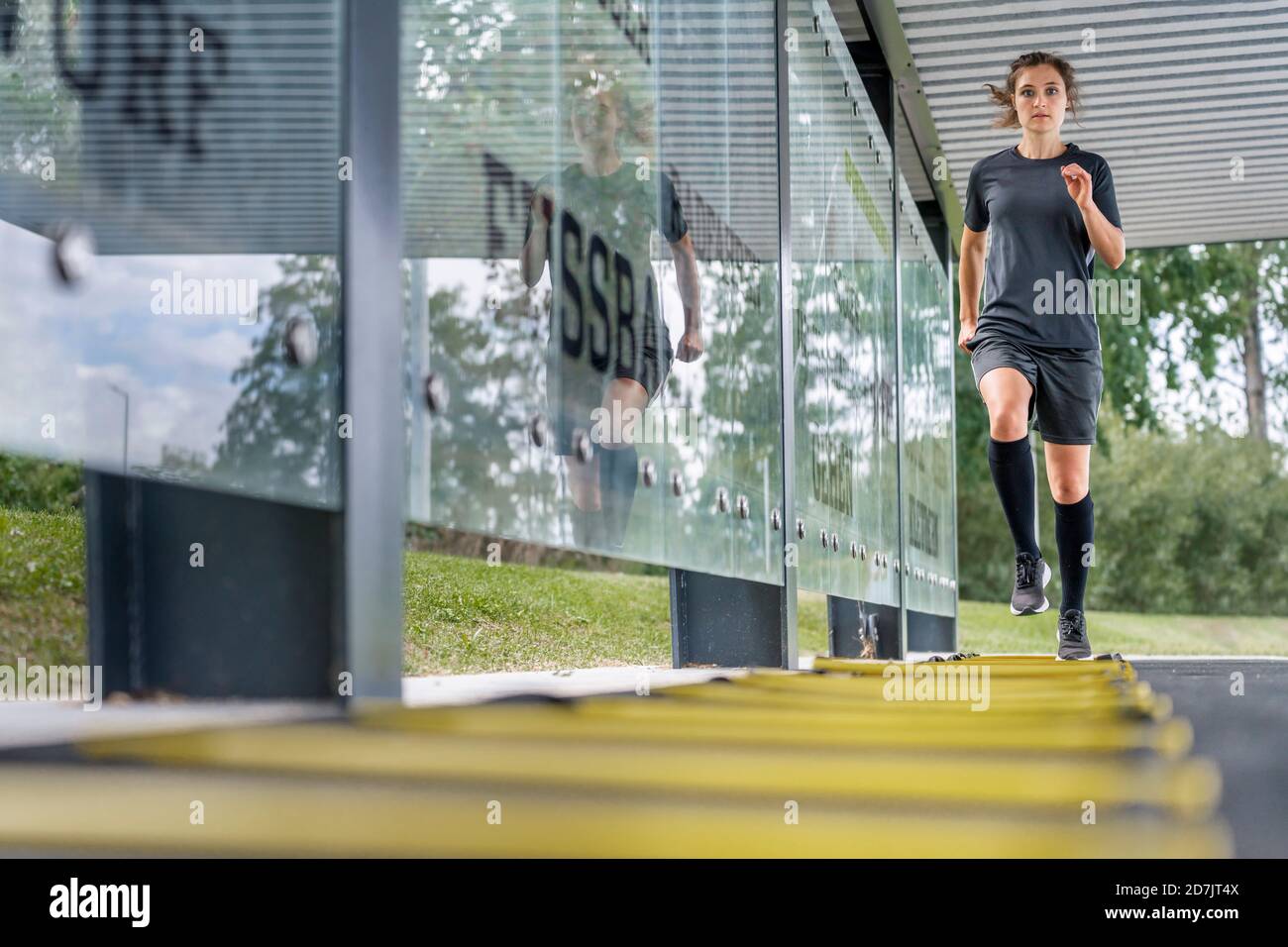 Confident female athlete jumping over small hurdles Stock Photo - Alamy