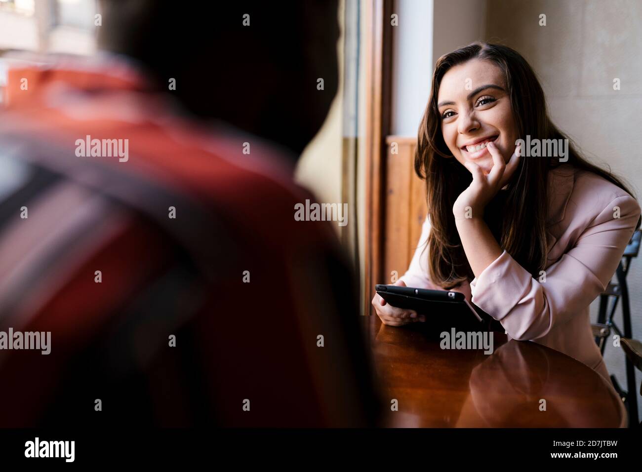 Smiling young woman talking with boyfriend in cafe Stock Photo - Alamy