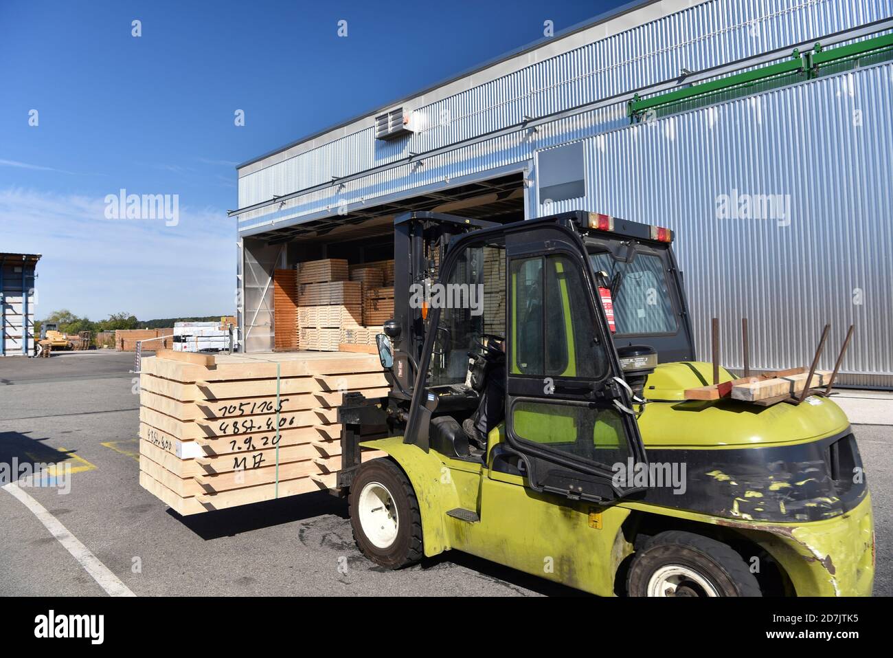 Forklift stacking planks inside lumberyard warehouse Stock Photo - Alamy