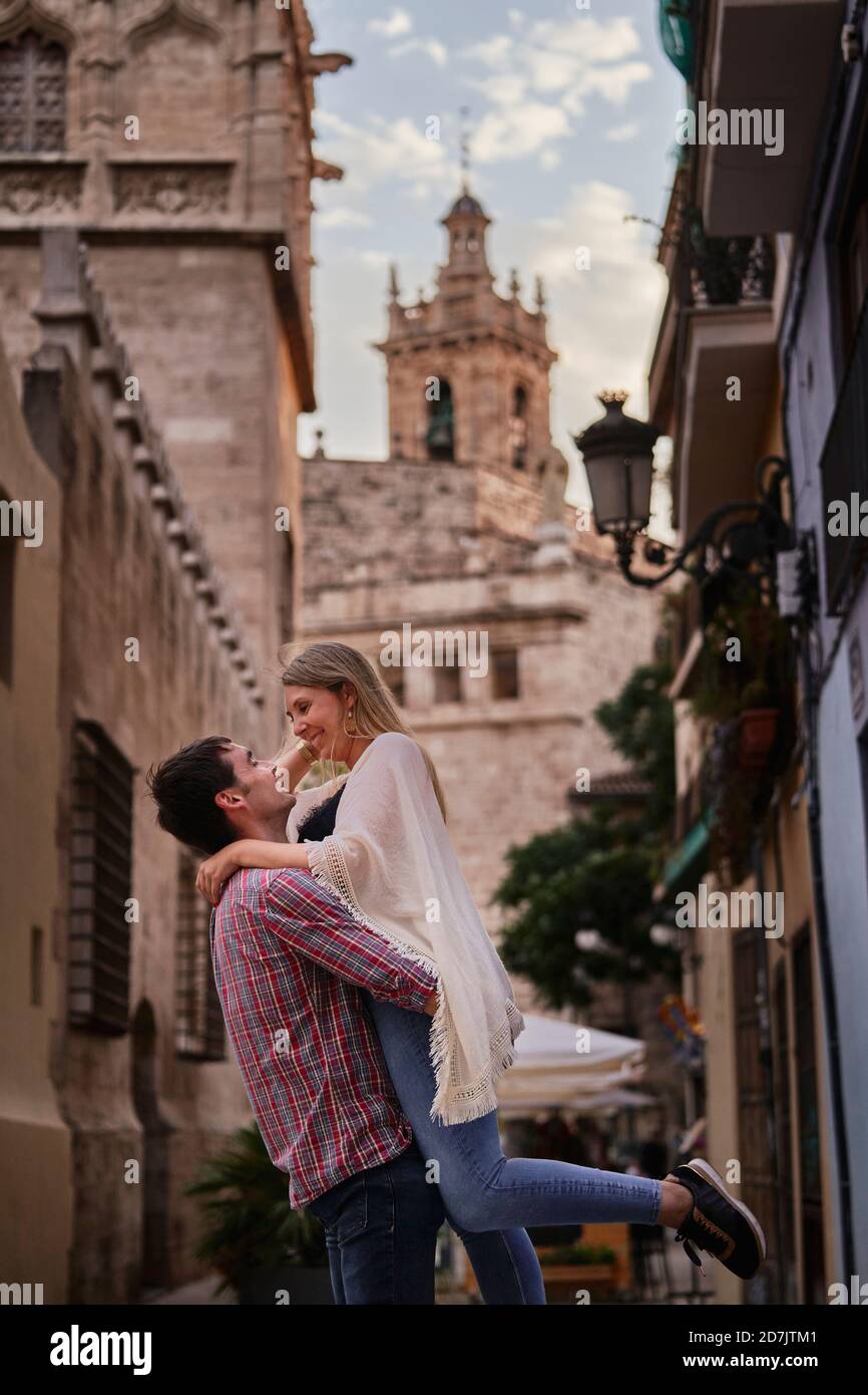 Happy man picking up woman while standing in city Stock Photo - Alamy