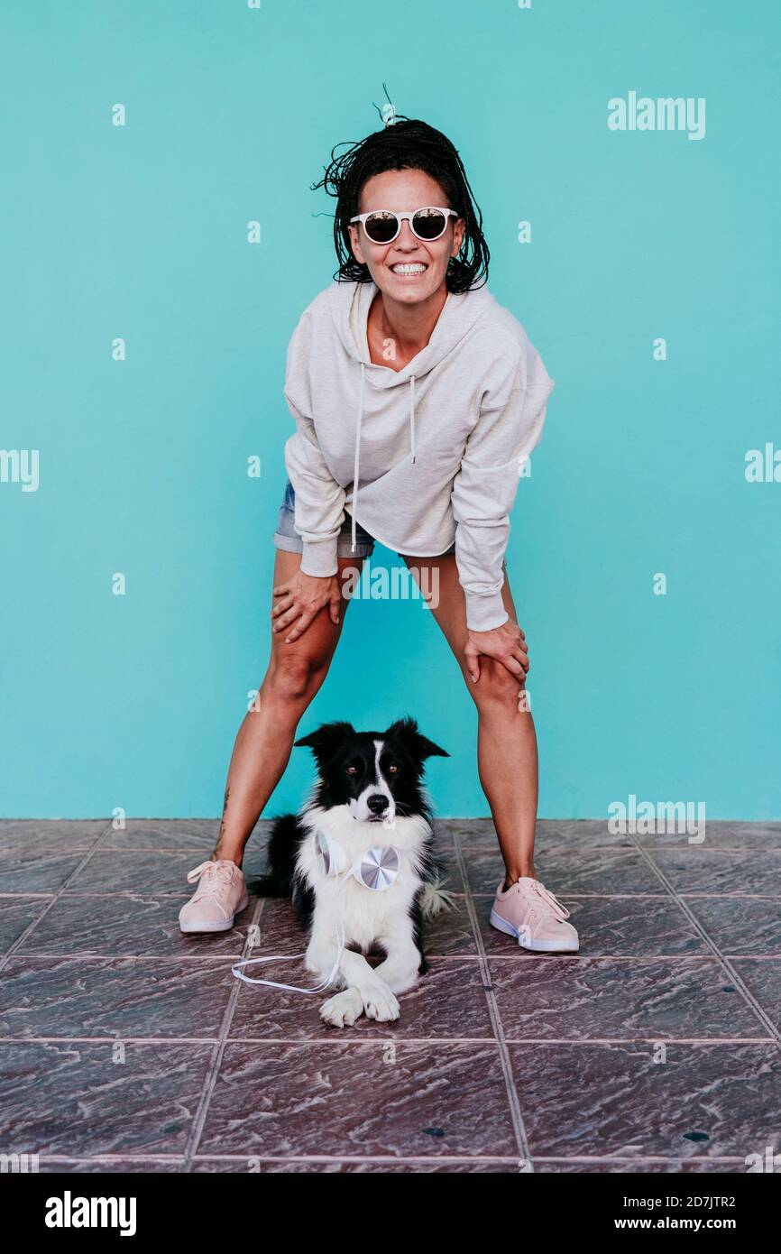 Happy woman bending over Border Collie dog against turquoise wall Stock ...