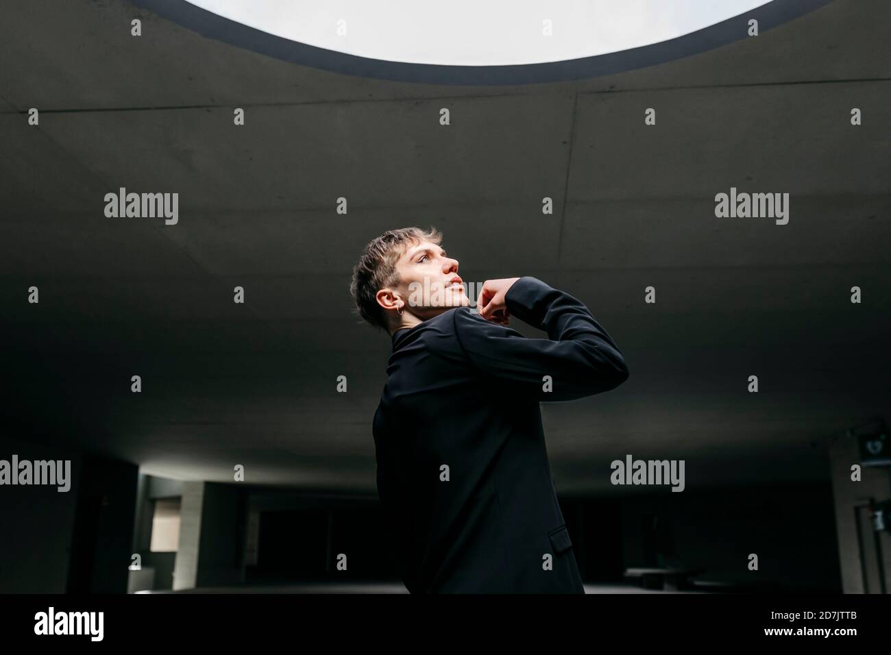 Non-binary man wearing black suit dancing in basement Stock Photo - Alamy