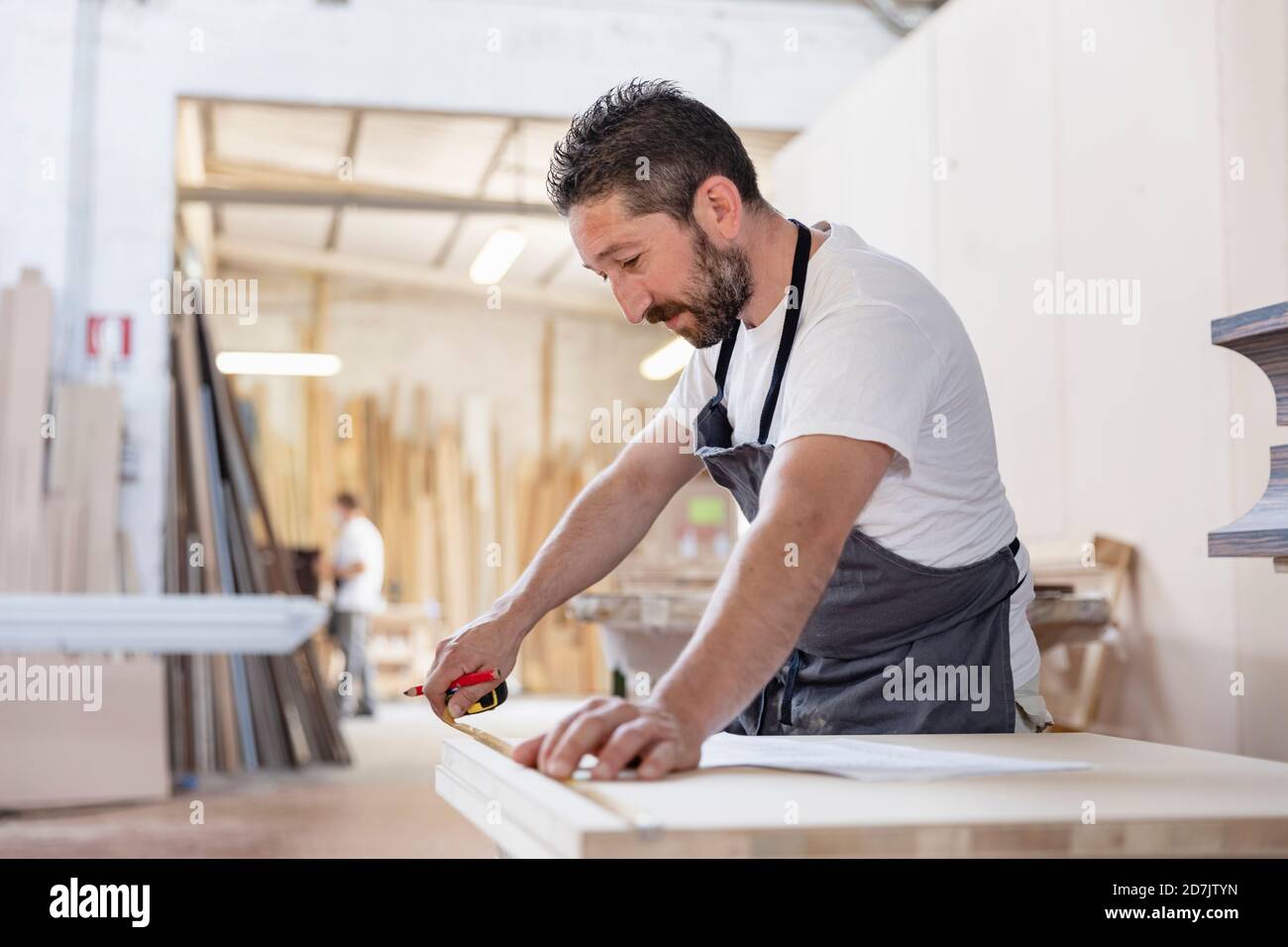 Man measuring wood with measurement tape while standing at workshop ...