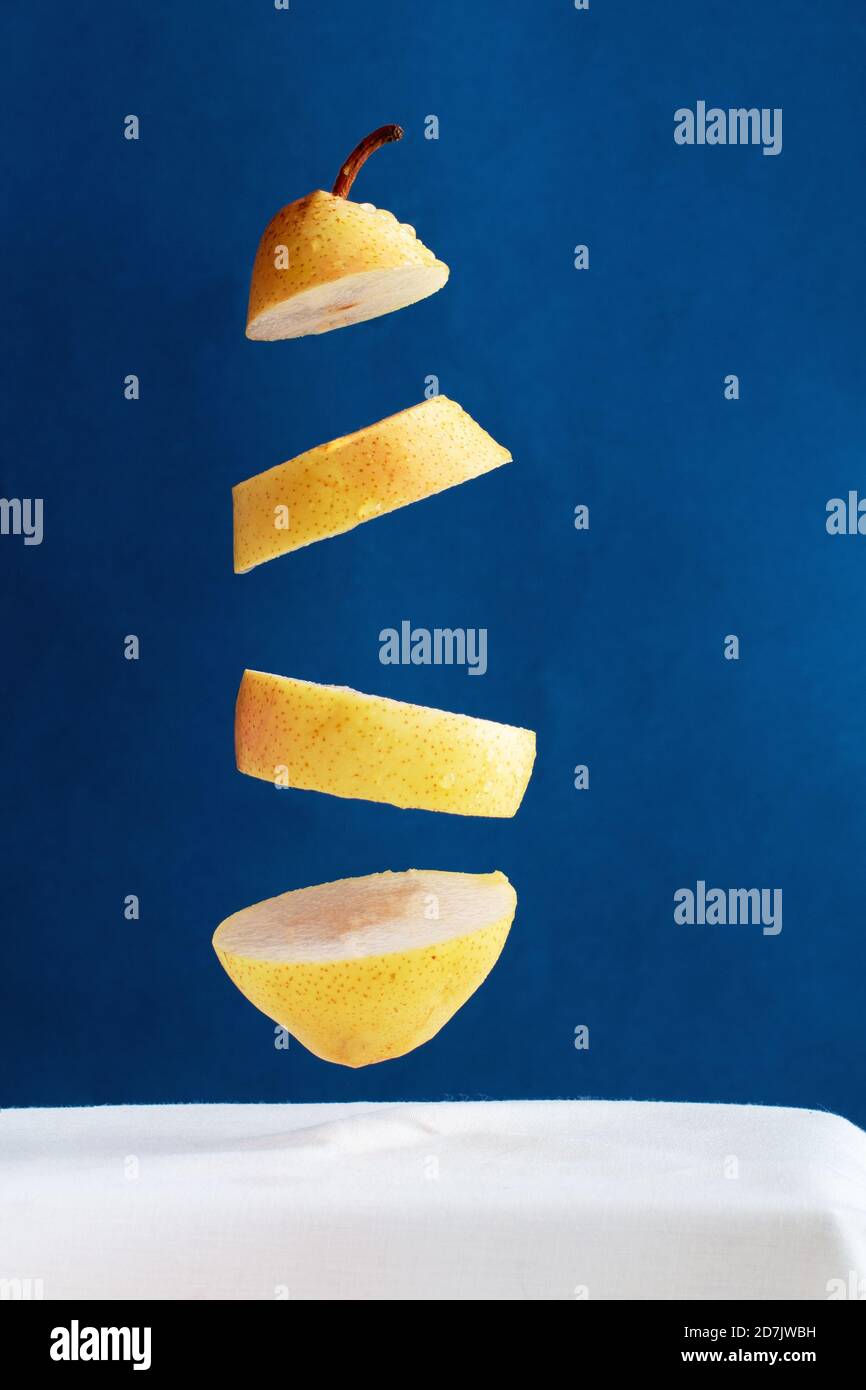 floating pieces of yellow pear against blue background, creative ...