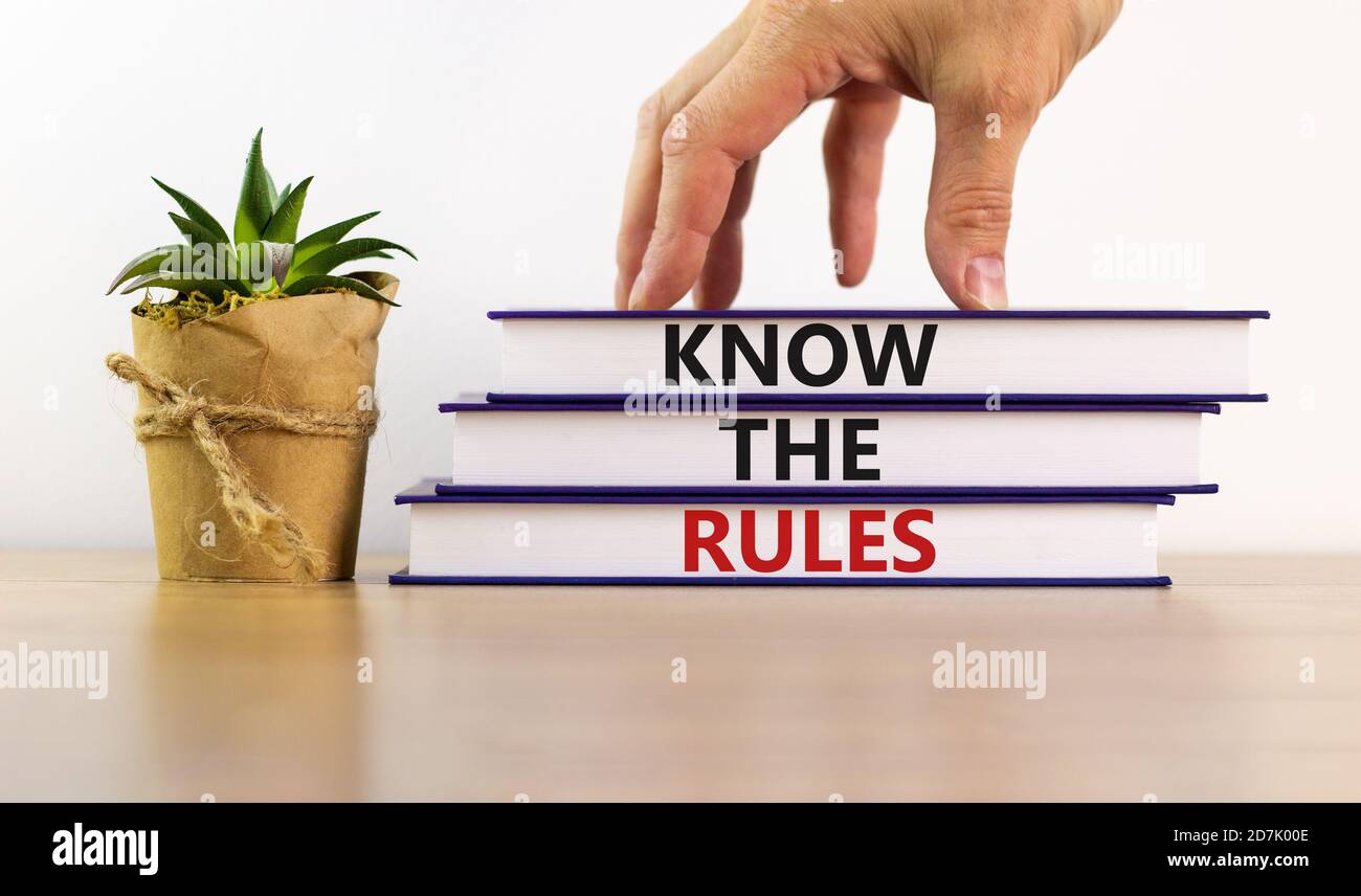 Books with text 'know the rules' on beautiful wooden table. Male hand ...