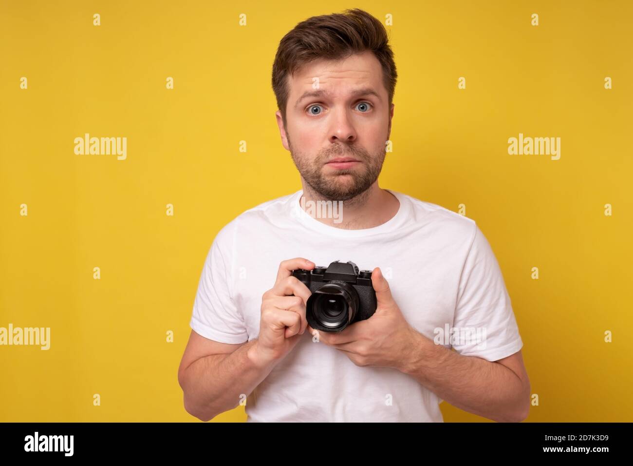 Studio portrait of handsome young man holding photocamera being ...