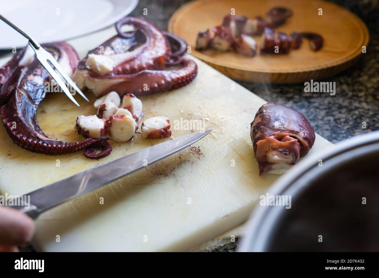 Cutting octopus with knife on kitchen table. Concept of Seafood Stock ...