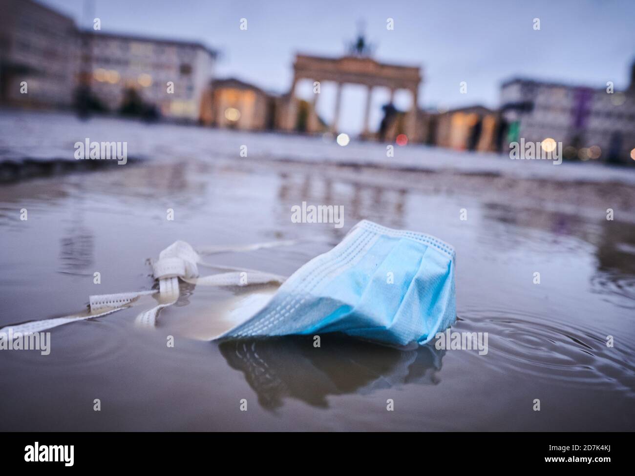 23 October 2020, Berlin: A mask lies in a puddle of rain in front of ...