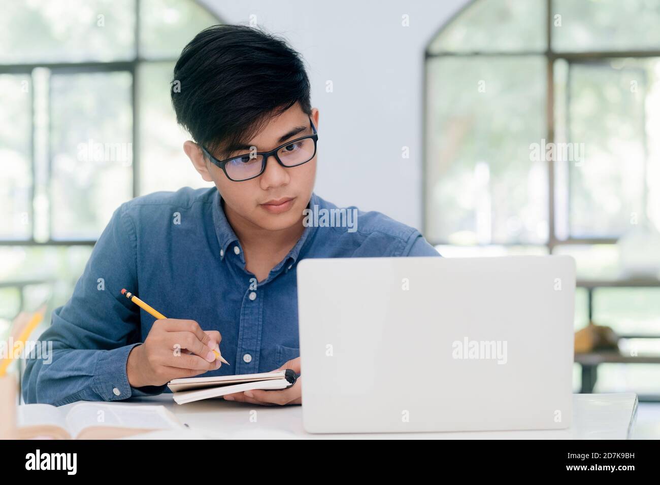 Young collage student using computer and mobile device studying online ...