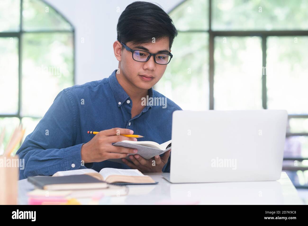 Young collage student using computer and mobile device studying online ...