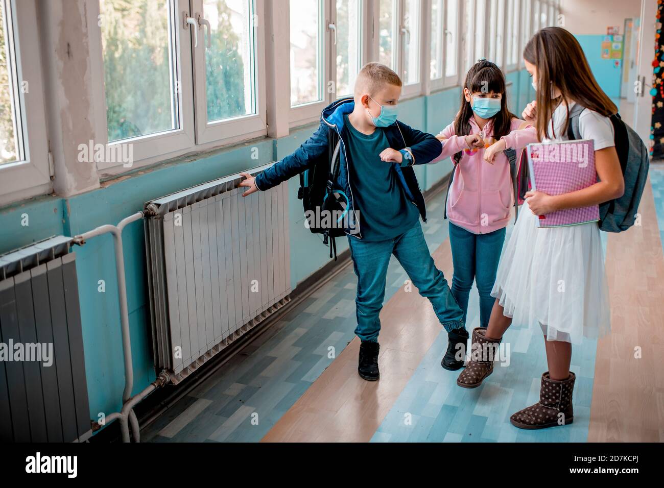 Elementary students greet with elbow bump and foot tap Stock Photo - Alamy