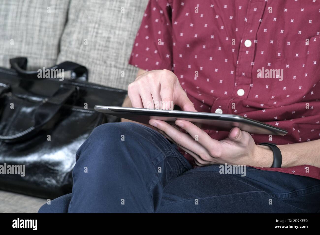 The young man sat down on the sofa in the office with his legs crossed ...