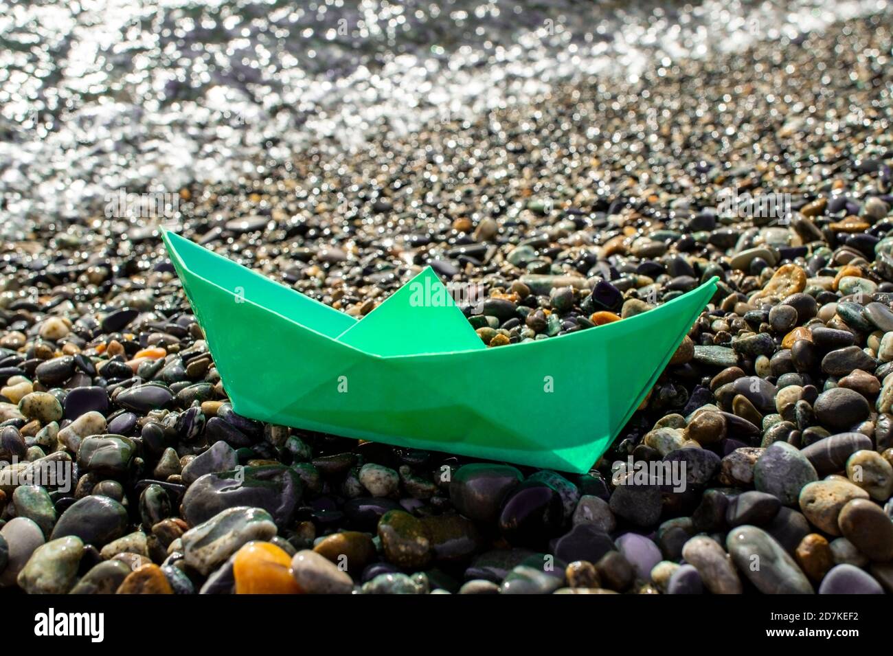Green paper boat close-up of a pebble beach on the background of the ...