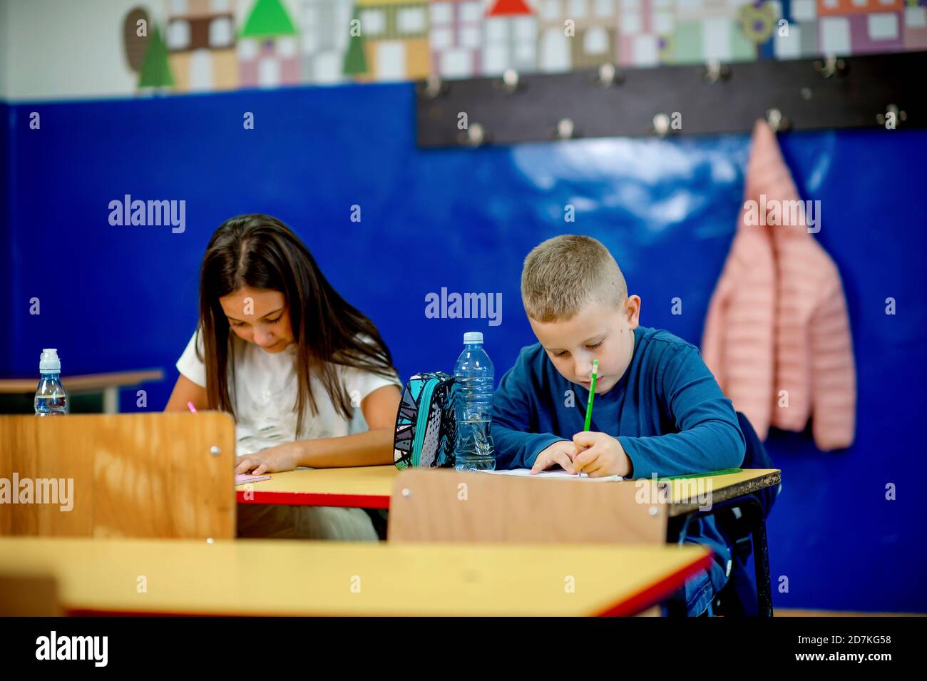 Elementary schoolchildren writing at the desk in the classroom Stock ...