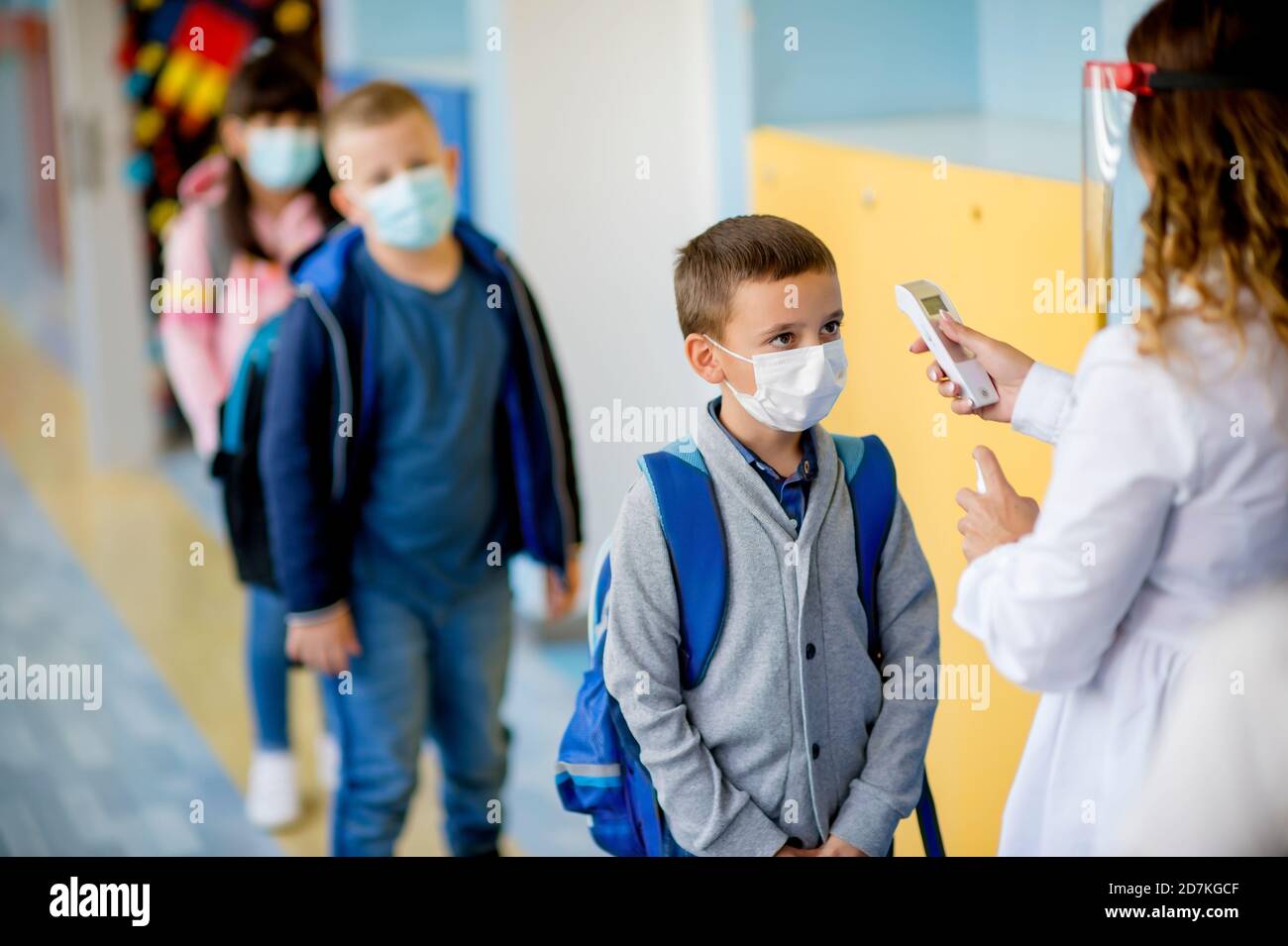 Teacher doing temperature check on school children Stock Photo - Alamy