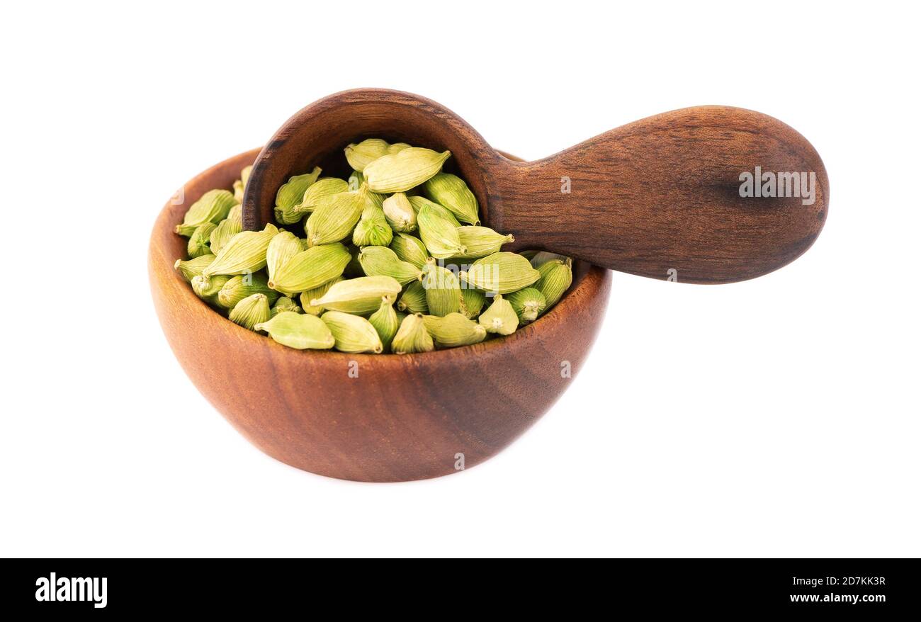 Cardamom seeds in wooden bowl and spoon, isolated on white background ...