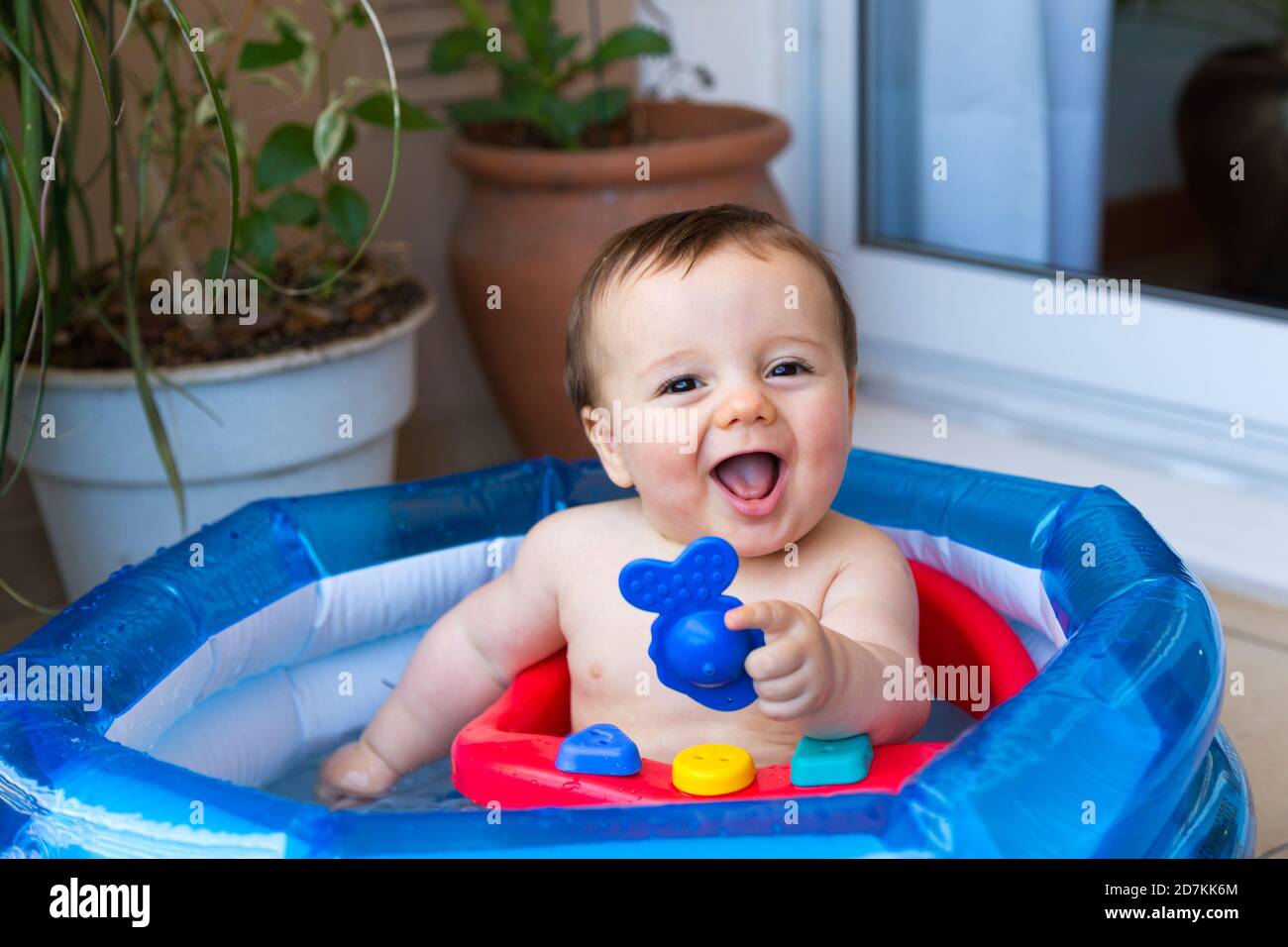 Baby taking a bath and playing in a little inflatable pool. Toddler ...
