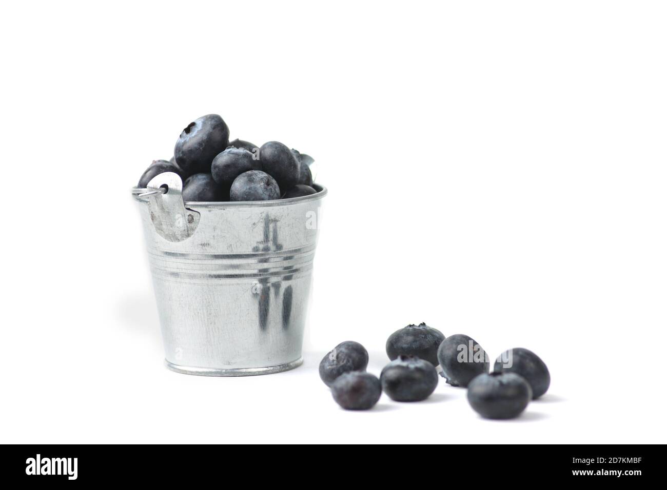 silver bucket of blueberry and a pile of berries isolated on white ...
