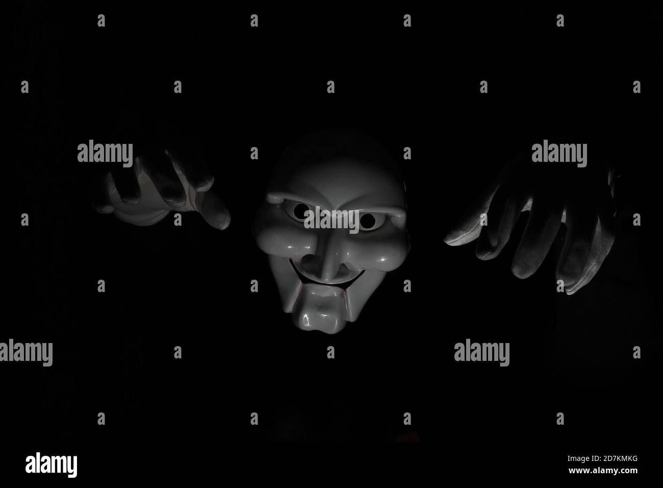 White scary mask on a black background with whites hand Stock Photo - Alamy