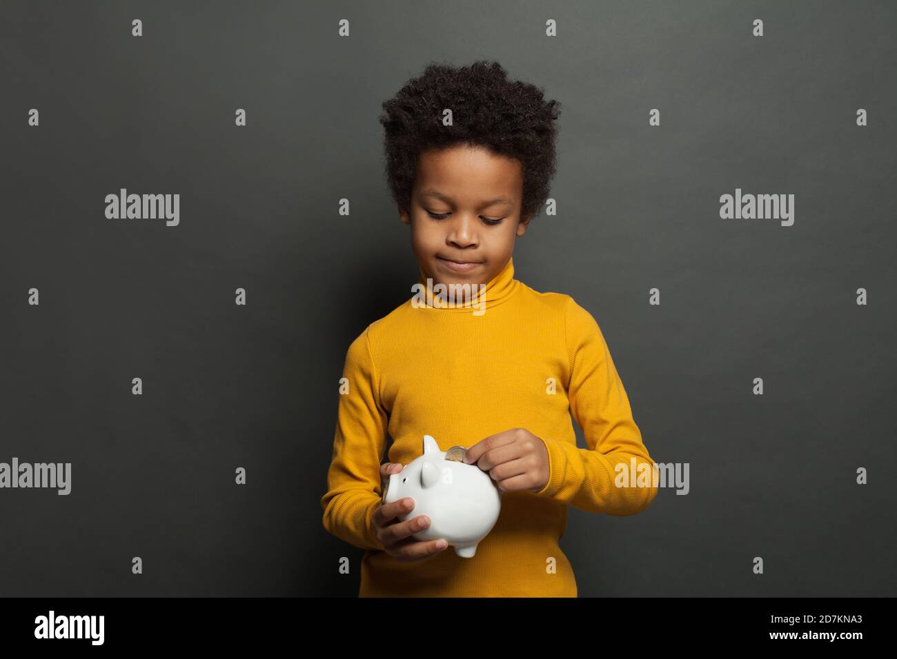 Cute black kid boy putting in money box coin Stock Photo - Alamy