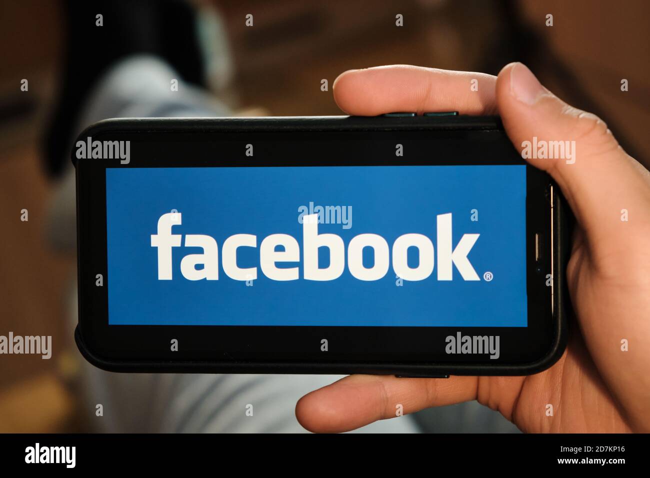 Facebook logo on the screen of a mobile phone in mans hand. Application ...